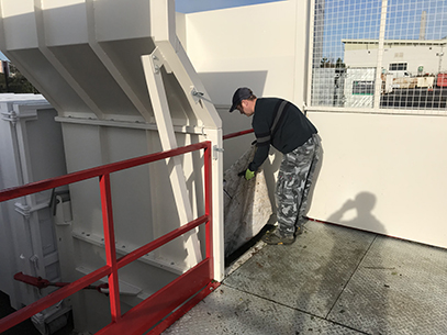 Green waste being emptied into static waste compactor - Gradeall ...